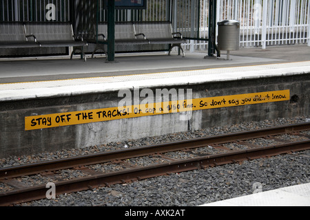 Warning sign on station platform edge with non slip paving and yellow ...