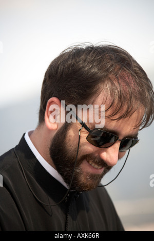 A Greek Orthodox Priest, wearing sunglasses. Pictured at a mass baptism ...
