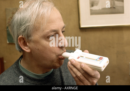 Peak flow meter. Man using a peak flow meter (spirometer) to measure ...