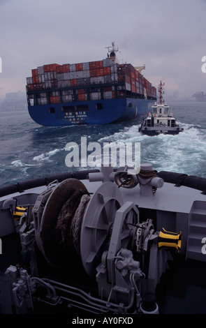 HUD tugboat in hong kong harbour behind huge container ship entering ...