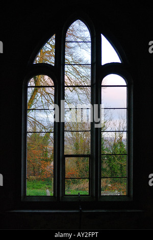 View through a glassless arched window of a derelict church burnt out ...