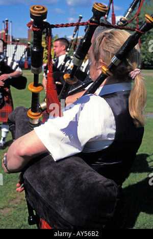 Young girl bagpiper playing bagpipes on street outside in Oban ...