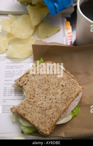 Office desk of busy office worker with bite out of sandwich Stock Photo ...