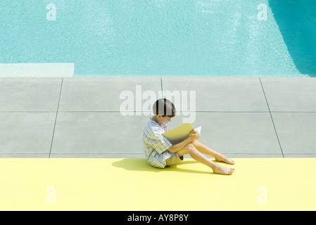BOY READING BY POOL Stock Photo: 21663466 - Alamy