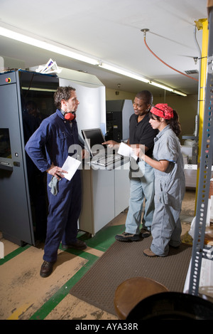 Workers being trained to use a piece of machinery with computer ...