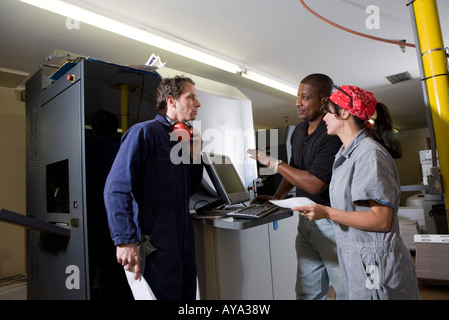 Workers being trained to use a piece of machinery with computer ...