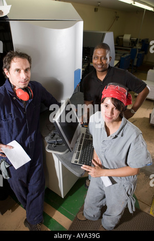Workers being trained to use a piece of machinery with computer ...
