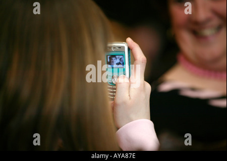 A wedding guest taking a photo with a camera phone of a bride and ...