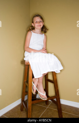 Girl sitting in corner on stool Stock Photo - Alamy