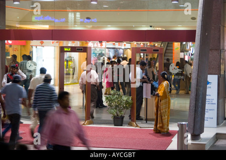 Contemporary security guard with metal detector checking one of ...