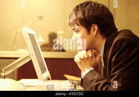 A young businessman staring at his computer screen for hours, rubbing ...