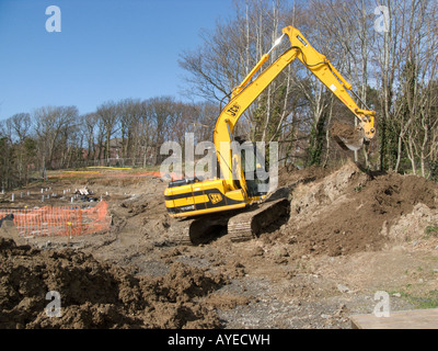 A yellow JCB digger clearing land in preparation for building work ...