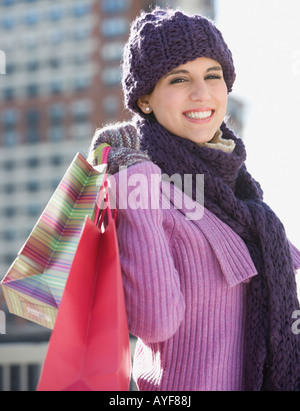 Young adult woman carrying shopping bags and smiling in a bright ...