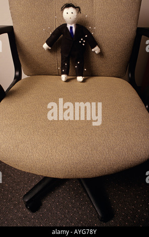 Voodoo doll standing in chair in office dressed as a business man in a ...