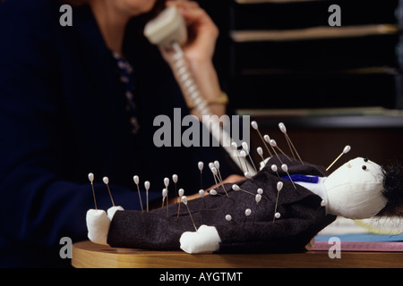 Voodoo doll lying on office desk with pins stuck in his body with a ...