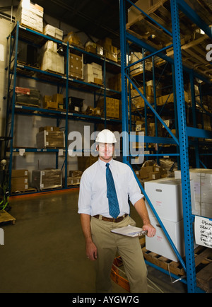 Worker standing with clipboard in warehouse Stock Photo - Alamy