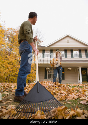 Smiling man carrying rake while standing in yard Stock Photo - Alamy