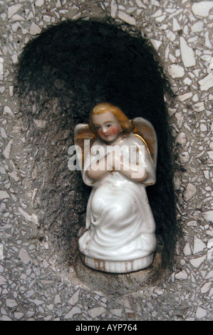 Small white praying angel statue sitting in its wings surrounded by ...