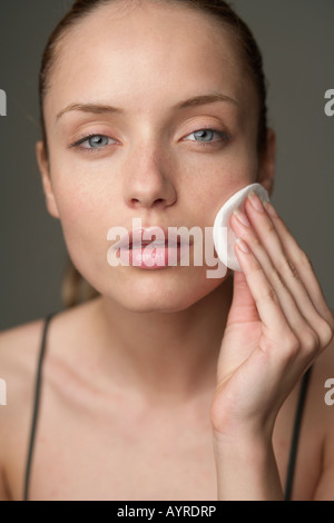 Young woman removing makeup with cotton pad on beige background Stock ...