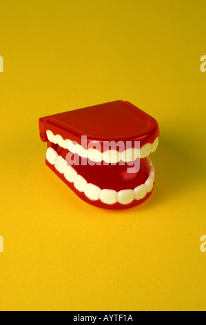 A plastic toy mouth with teeth and tongue on a light blue background ...