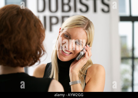 Two young women vis-à-vis, one woman phoning with a mobile phone Stock ...