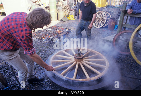 Wheelwright's at work ( tyring the wheel ) putting a metal hoop around ...