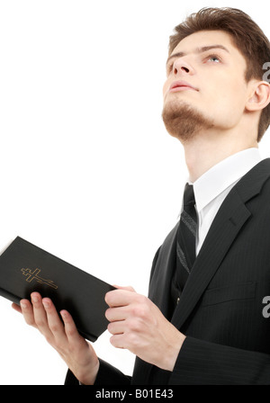 Young man with Holy Bible praying on white brick background Stock Photo ...