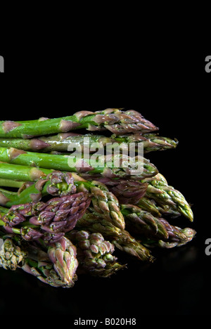 Bundle of green asparagus on black background and light effect. Close ...