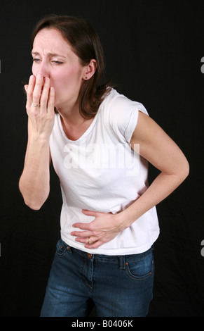 Young woman holds stomach and covers mouth while retching before ...