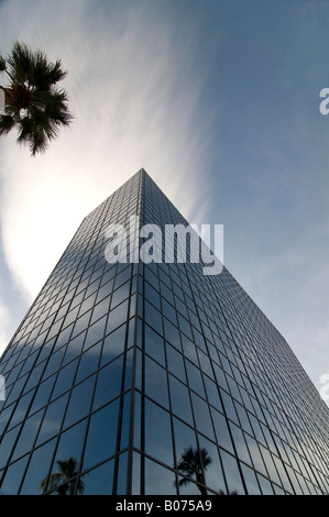 A modern high rise office tower with blue glass windows and blue sky ...