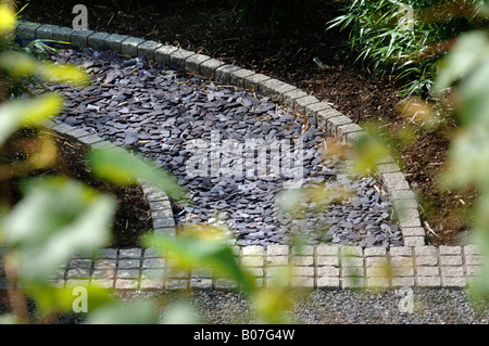 A PATH LAYED WITH SLATE SHARDS EDGED WITH GRANITE COBBLES AND BEDS ...