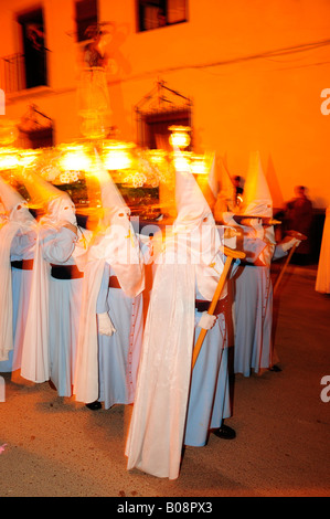 Penitents dressed in penitential robes (nazareno) carrying crosses ...