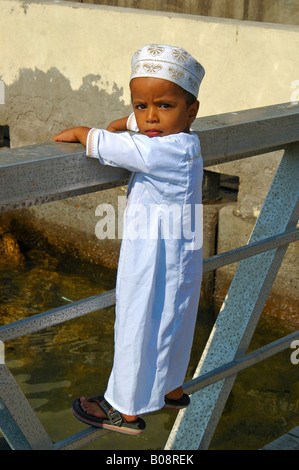 Oman, Muscat, children in traditional dress looking at pictures Stock ...