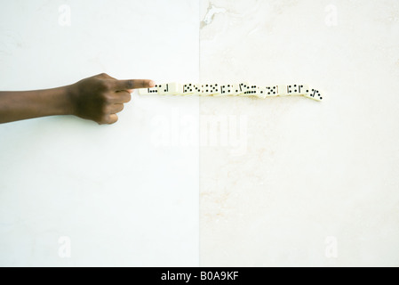 Child knocking over line of dominoes, cropped view of hand Stock Photo ...