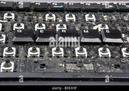 A dirty computer keyboard with crumbs of food between the keys ...
