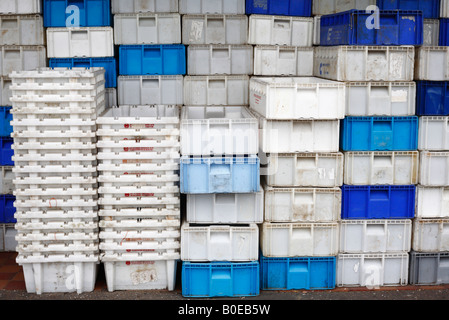 Blue plastic fish boxes stacked up at the harbour of a fishing village ...