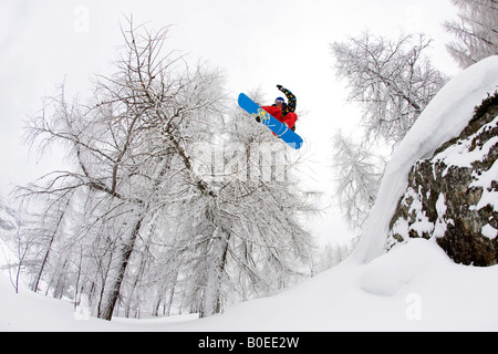 Snowboarder jumps from a rock off piste Stock Photo - Alamy