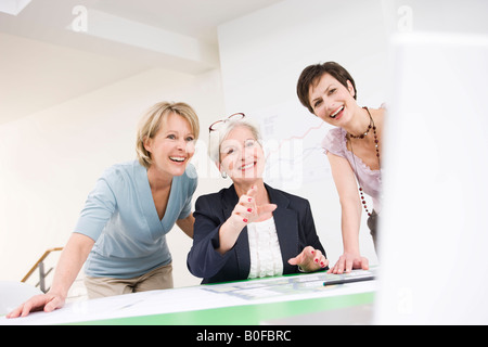 Discussing three women in business attire reviewing charts at ...