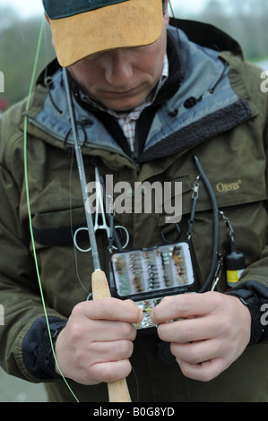 A mans hands holding a fly ready to go fly fishing. Fishing Tackle ...