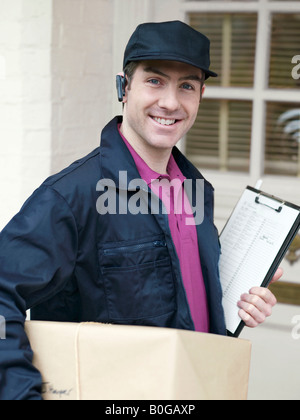 Courier with large parcel at front door Stock Photo - Alamy