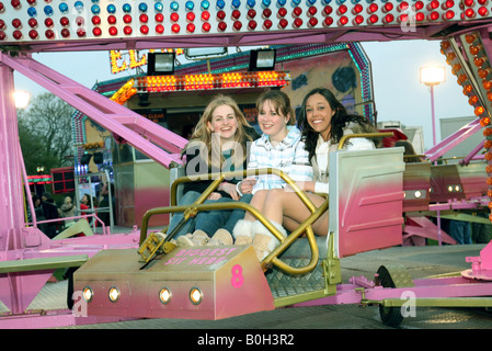 Three teen girls enjoying the rides at the funfair, the fairground ...