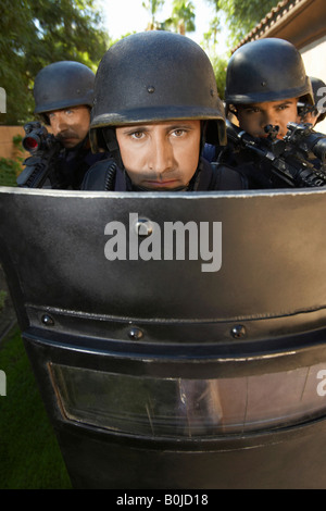 Swat officers behind shield Stock Photo - Alamy