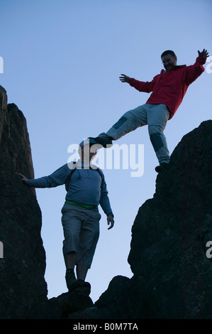 Man stepping across a gap in some rocks Stock Photo - Alamy