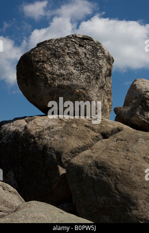 A granite boulder perched with blue sky background near the peak ...