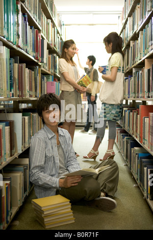 Students standing by bookshelf in the library Stock Photo - Alamy