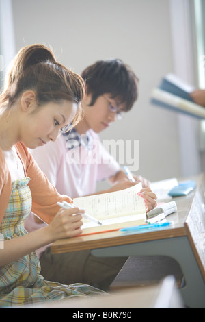 Asian women reading book at desk with laptop computer for professional ...