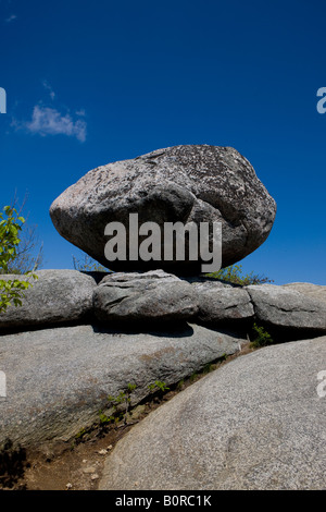 A granite boulder perched with blue sky background near the peak ...