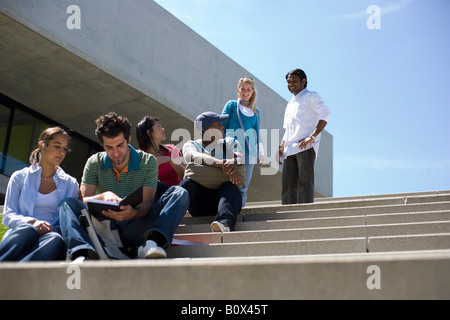 Three students talking or socializing at university campus - Friends ...