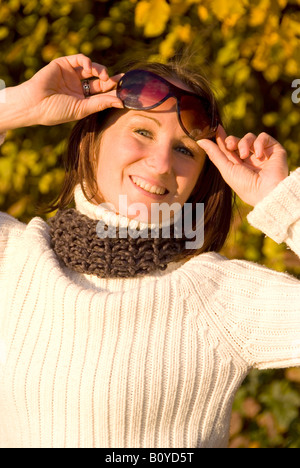 young woman in a white pully, lying and throwing with autumn foliage ...