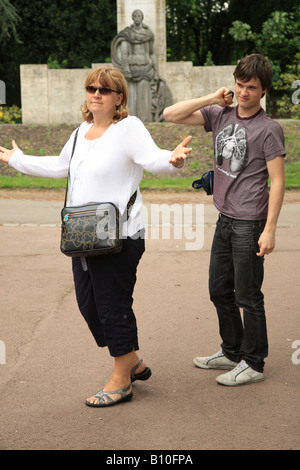 Sad mother and son standing with hands crossed and looking down after ...